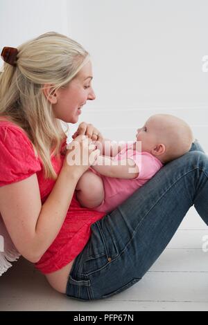 Side view of mother sitting propped up with pillows with baby resting ...