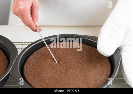Chocolate Cake, inserting a skewer to test if cake is done Stock Photo ...