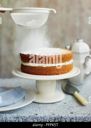 Dusting Victoria sponge cake with icing sugar Stock Photo - Alamy