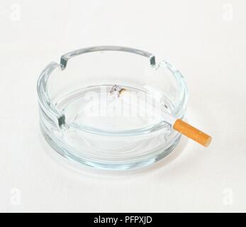 Lit cigarette burning in ashtray close up Stock Photo - Alamy