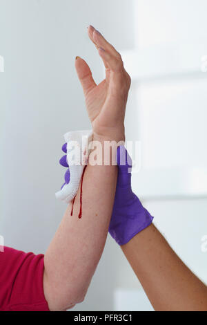 Applying first aid to the injured bleeding man, wearing tourniquet on ...