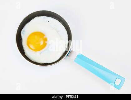 Egg being cooked in blue frying pan Stock Photo - Alamy