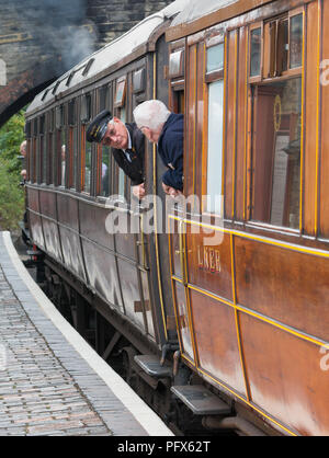 Steam train conductor leaning out of passenger car window Stock Photo ...