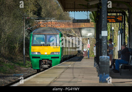 Class 321 passenger train in London Midland livery arriving at a small ...