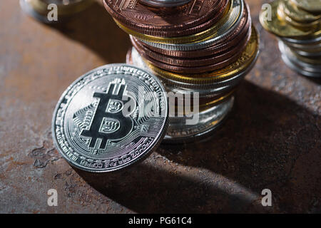 close up view of bitcoin leaning on stack of various bitcoins on black ...