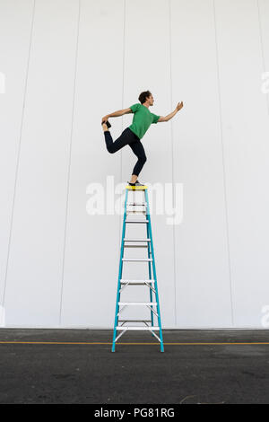 Acrobat balancing on ladder Stock Photo - Alamy