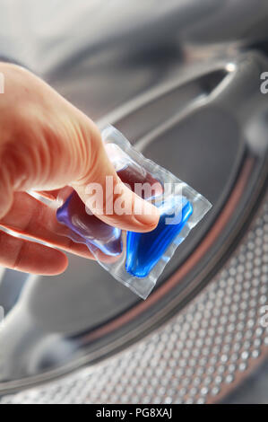 blue gel caps in hand for washing mashine, liquid coloured detergent ...