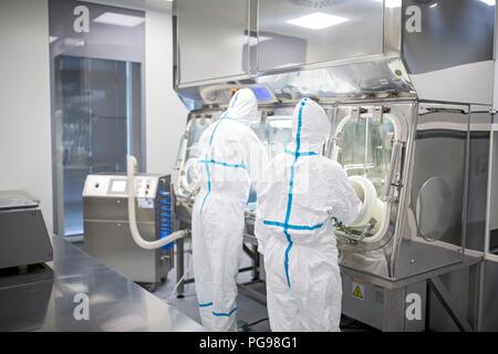 Technicians working in sealed, sterile isolator units in a laboratory ...