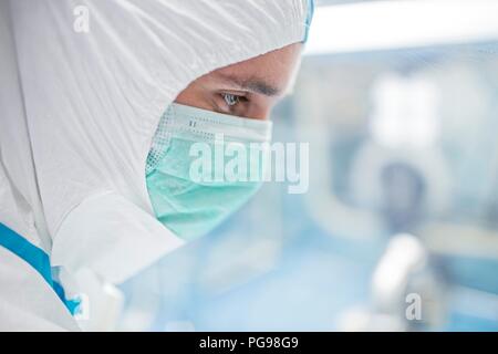 Lab technician wearing a protective suit and face mask in a laboratory ...