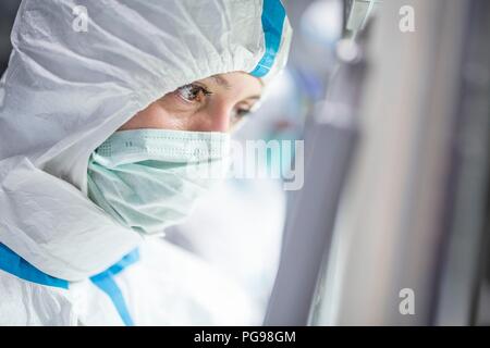 Lab technician wearing a protective suit and face mask in a laboratory ...