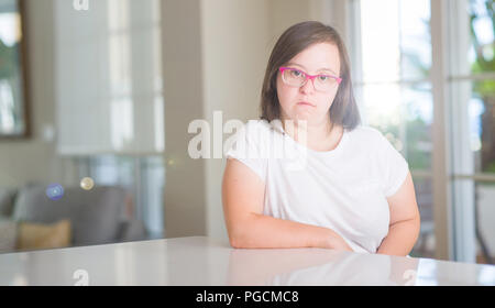 Down syndrome woman at home with a confident expression on smart face ...