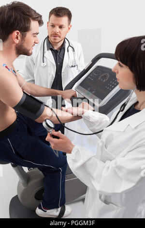 Man patient, pedaling on a bicycle ergometer stress test system for the ...