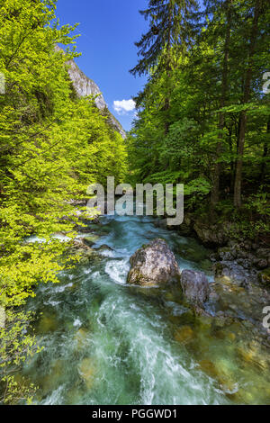 A long exposure of a small cascade flowing through rocks covered with ...
