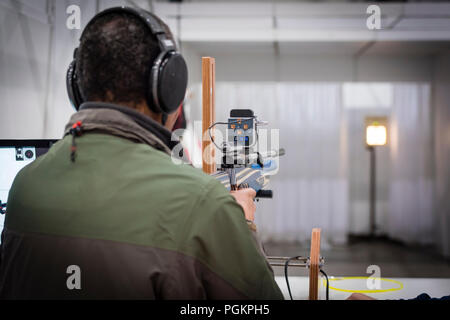 A blind man is aiming a specially equipped rifle at the target on a ...