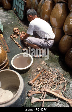 A Man removes bones from a earthenware earthenware jar and washes them ...