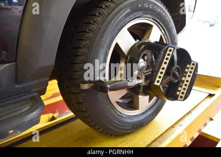 Tyre/tire fitting: a mechanic on the underside of a vehicle adjusting ...