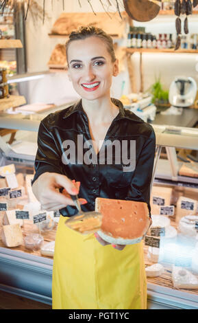 Beautiful woman offering cheese on delicatessen counter Stock Photo - Alamy