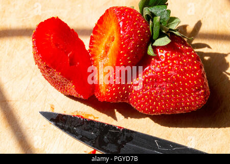 Close up of one cut strawberry on a pile of fresh ripe strawberries ...