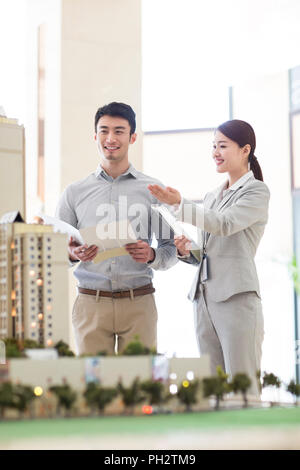 Realtor showing architectural model to young man Stock Photo - Alamy