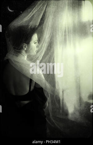 Dark mood photo of a woman while standing in the forest and reaching up ...