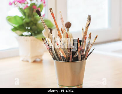 Different brushes of the artist in a metal bucket, selective focus ...
