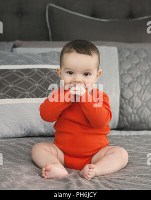 Cute baby girl with red clothes sitting on the floor and playing with ...