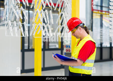 Factory supervisor checking production line holding blue folder with ...
