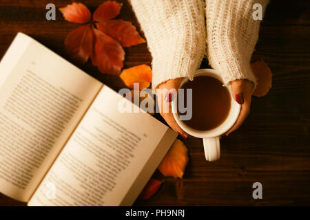 Woman hands holding teacup and opened book seen from above in vintage ...