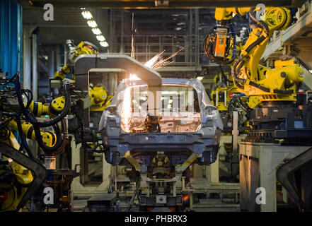 Robots get to work on the body of a new Nissan Motor Co. vehicle at the ...