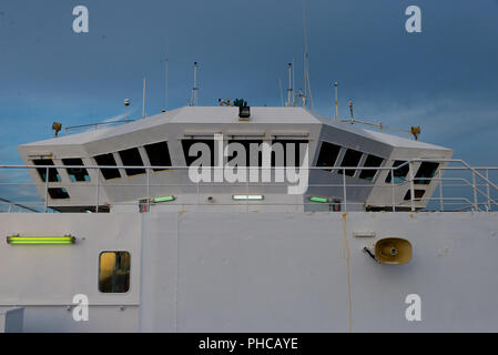 A cargo ship's bridge and control deck with antenna and spotlights ...