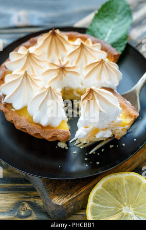 Tartlet with Italian meringue and lemon cream on a wooden stand ...