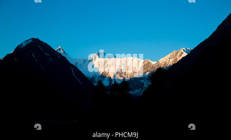 The first rays of the sun fall to the top of the mountain Stock Photo ...