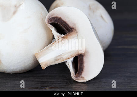 cut into half and pieces of white champignon on a black background ...