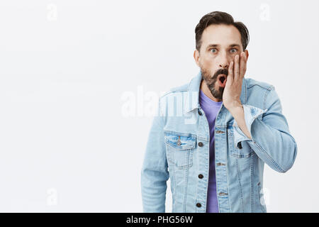 shocked bearded guy in denim shirt holding clipboard, making a ...