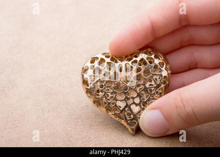 Heart shaped gold color metal object in hand Stock Photo - Alamy