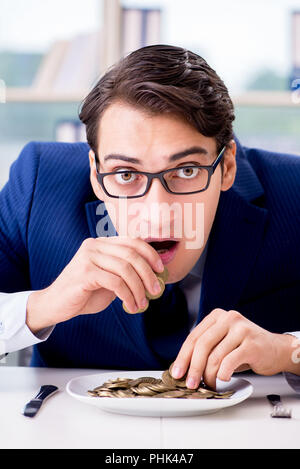 The funny businessman eating gold coins in office Stock Photo - Alamy