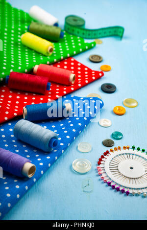 Sewing accessories and multi-colored fabrics on a blue wooden ...