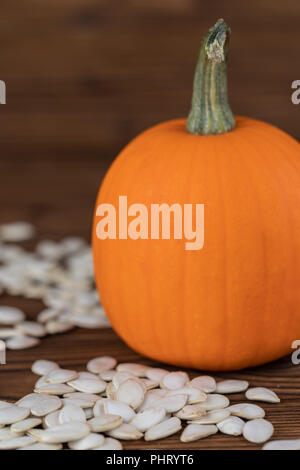 Fresh orange pumpkin and pimpkin seeds close-up on wooden background ...
