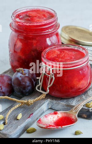 Wooden spoon with plum jam in a glass jar. Healthy food background ...