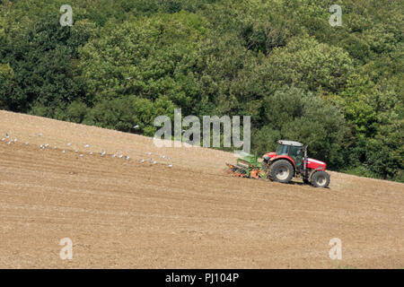 a large tractor pulling a plough across farmland or agricultural land ...