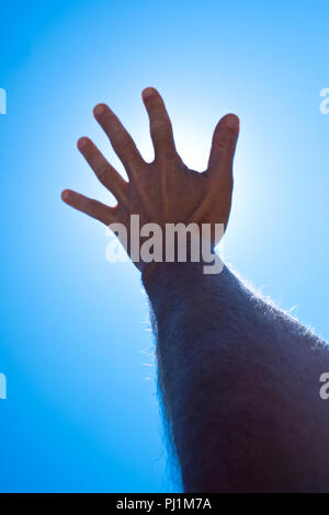 An outstretched hand reaches towards a blue sky with wispy clouds Stock ...