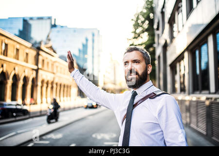 Handsome hipster man standing raising hands in the air in a yellow ...