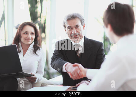 handshake Manager and client sitting at your Desk Stock Photo - Alamy