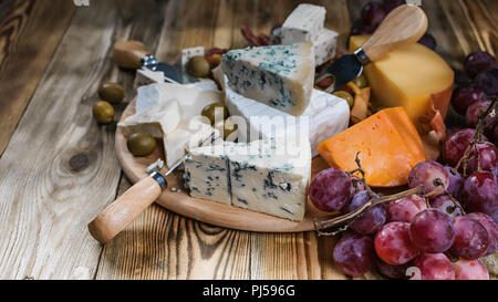 Different sorts of cheese and grapes on a wooden background. Close-Up ...