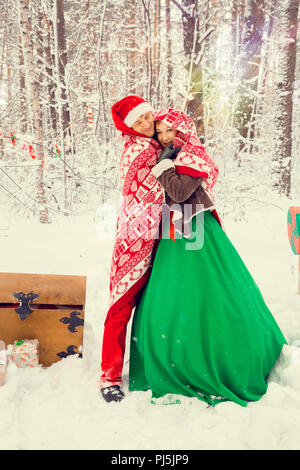 Young couple in Santa costumes with Christmas tree on white background ...