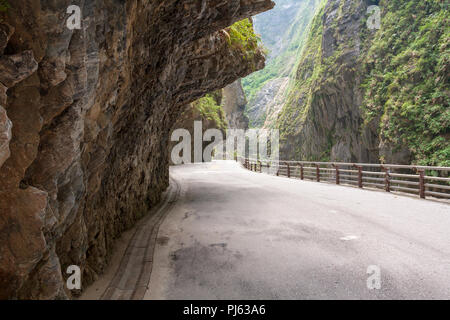 Cliffside road under rock overhang and stream flowing through marble ...