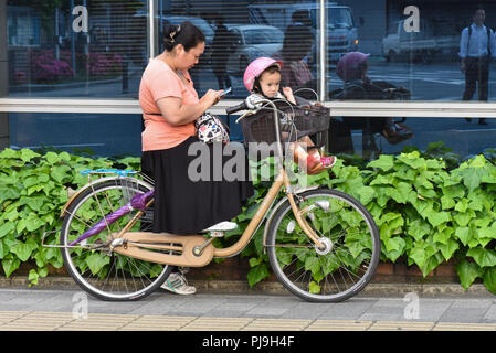 Daily Life in Japan Mother and young child walking through a small city ...