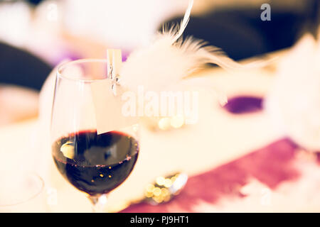 Red Wine Glass Feather Name Tag on Wedding Table Stock Photo - Alamy