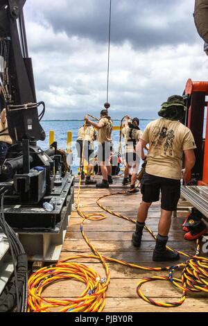 U.S. Navy divers conduct a ship's husbandry dive on USS Hue City Stock ...
