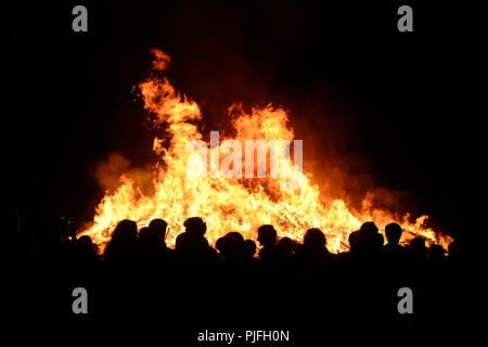 People are silhouetted against the flames of a large bonfire on the 5th ...
